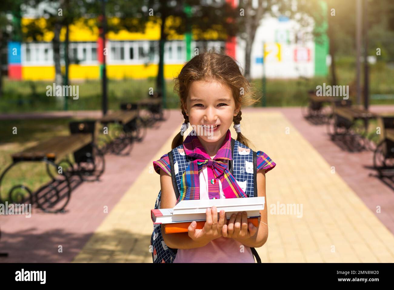 Girl with a backpack and a stack of books near the school. Back to ...