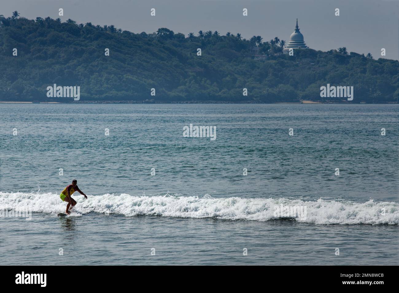 Male surfing in distance in Unawatuwa, Galle sea riding moderate wave ...