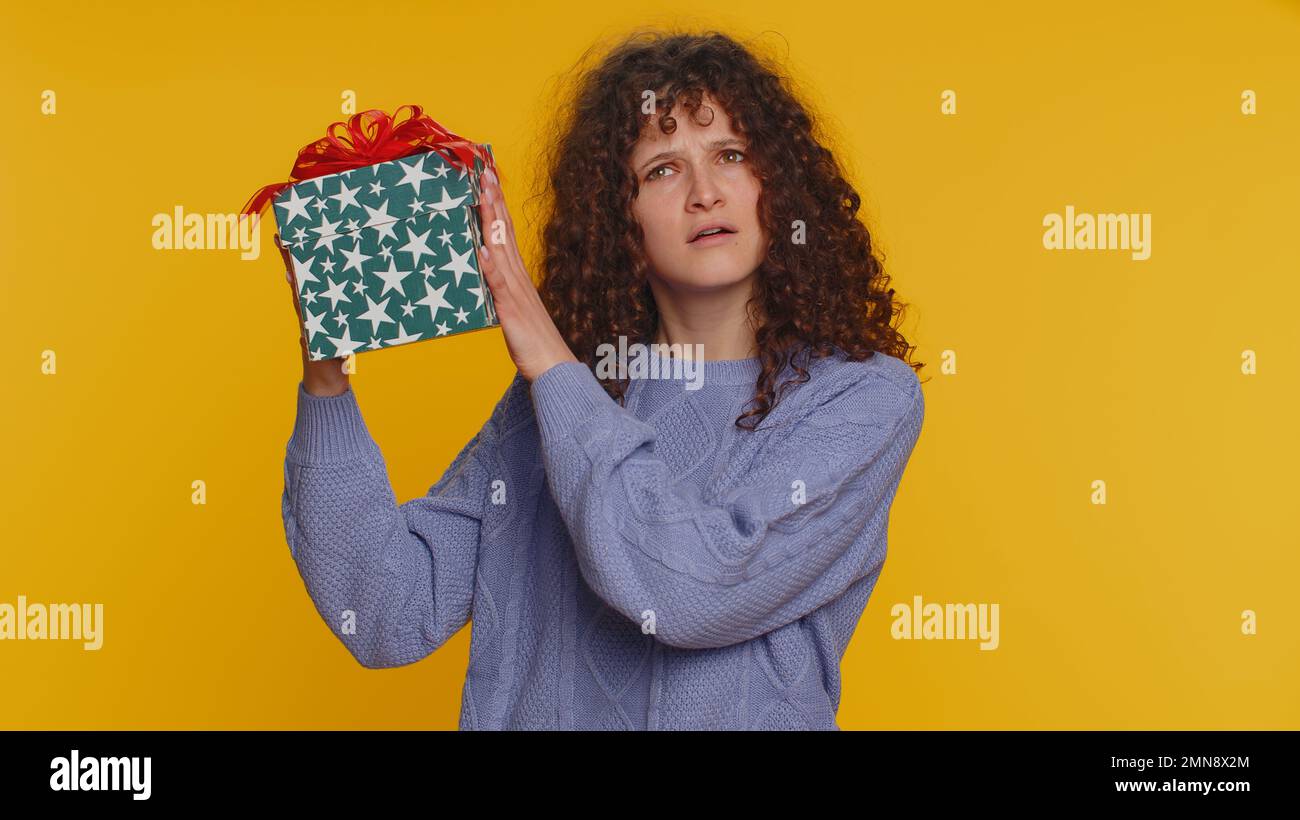 Happy curly haired woman opening gift box, unwrapping birthday surprise ...
