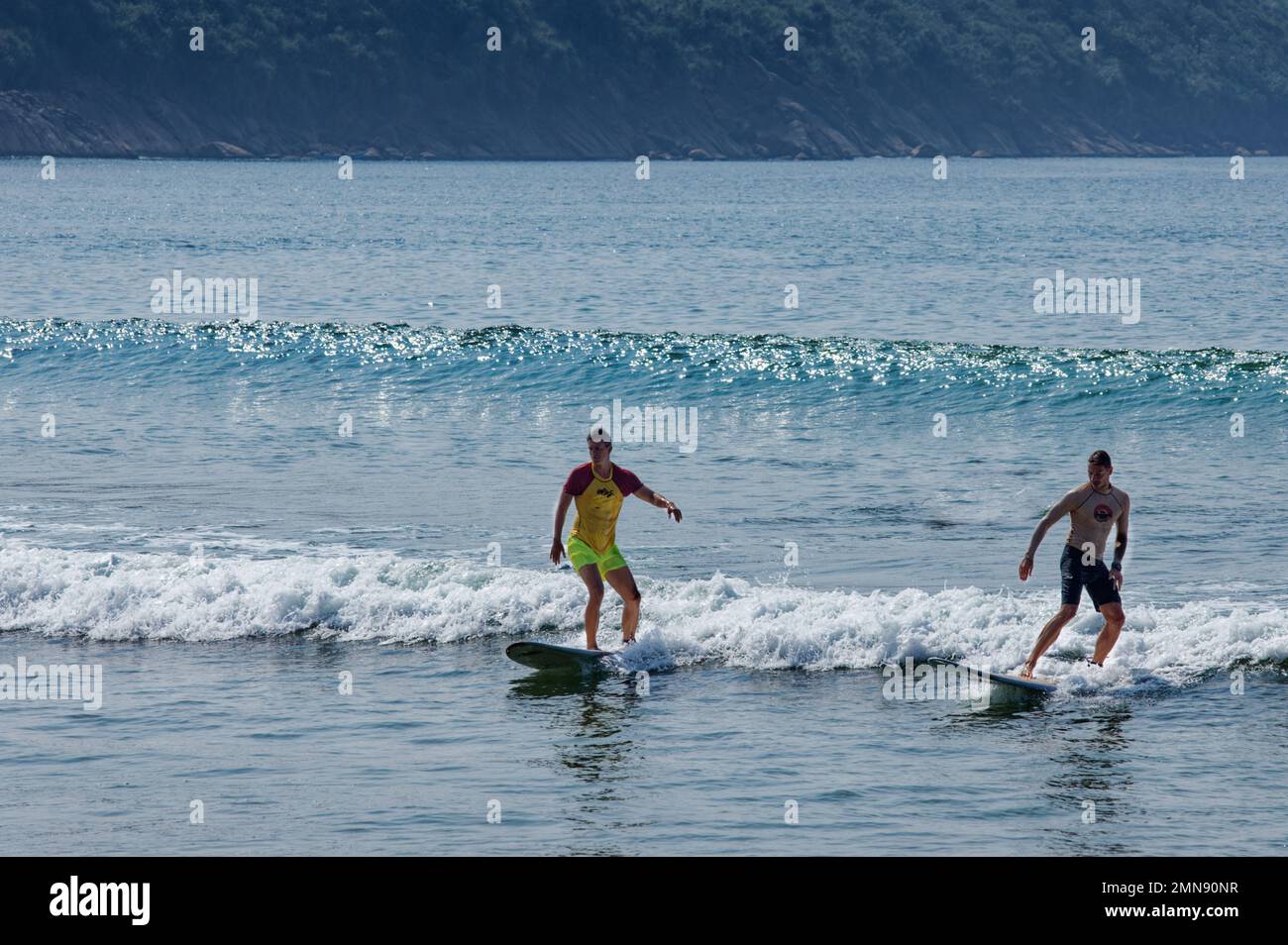 Two male athletes surfing in distance in Unawatuwa, Galle sea riding ...