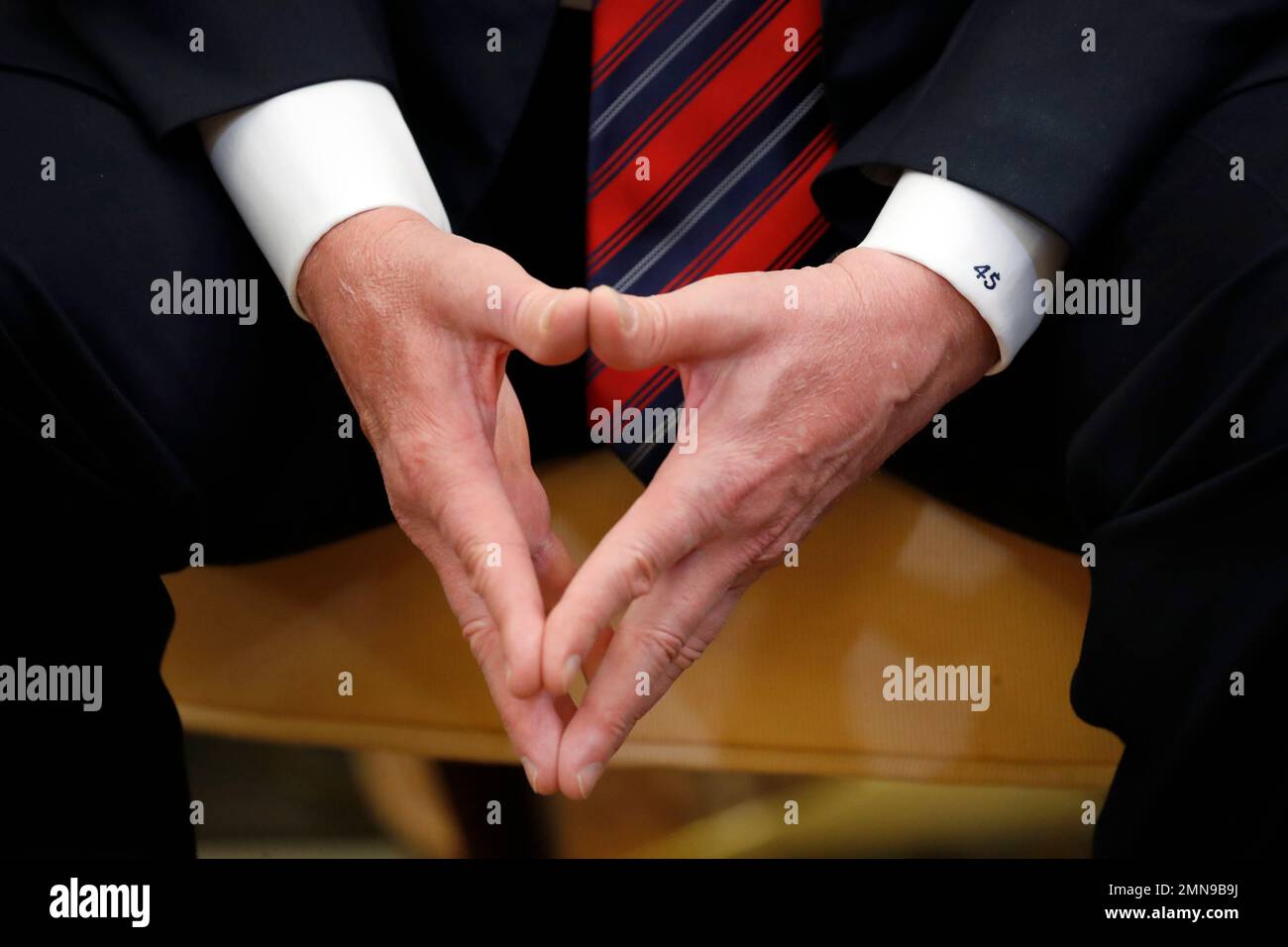 President Donald Trump holds his hands together, showing a monogrammed ...