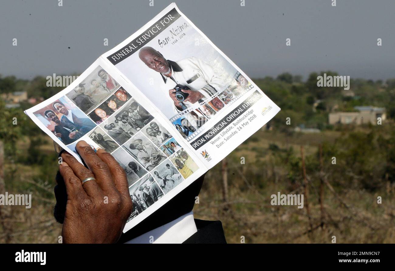 A mourner holds a funeral program of a photographer, Sam Nzima, know ...