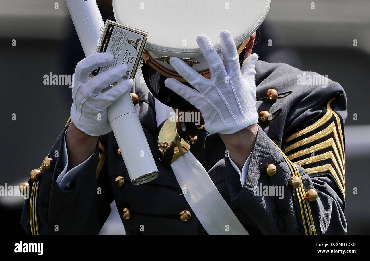 A West Point cadet catches her cap as it slips off her head after ...