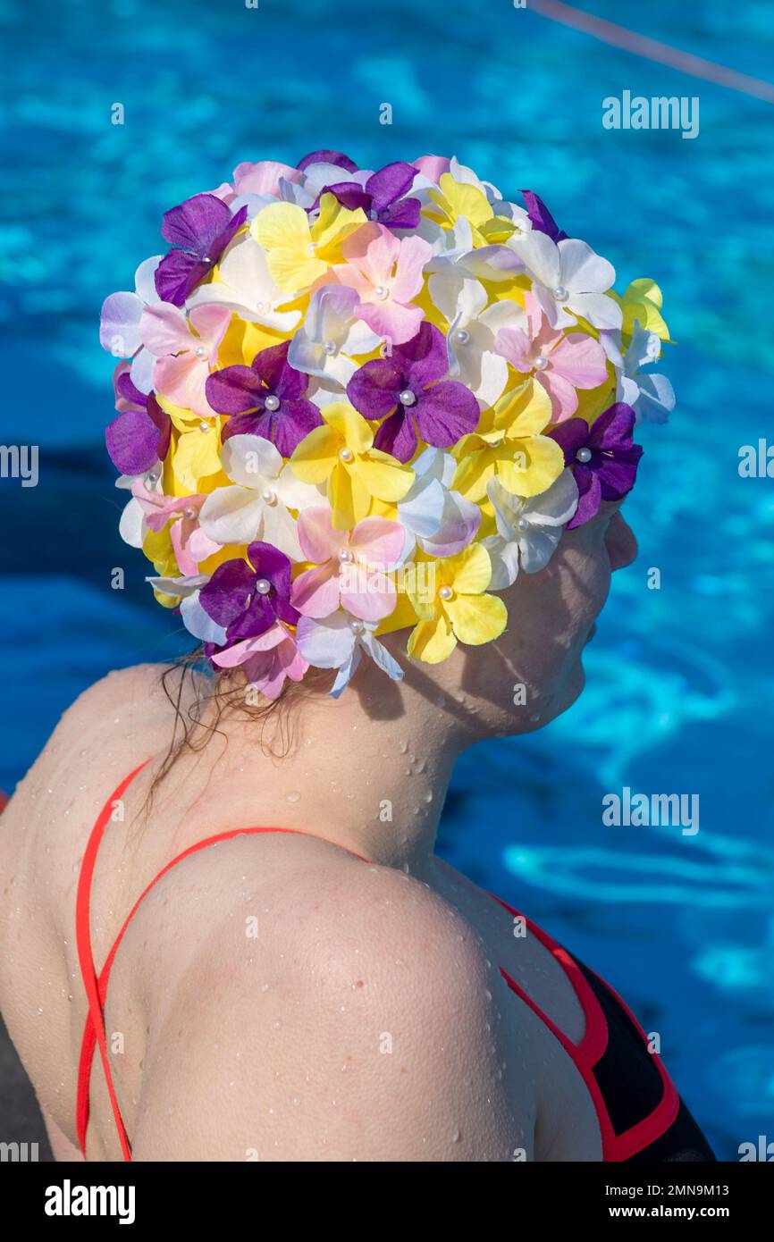 A portrait of a female swimmer sat by a pool wearing a frilly flower ...