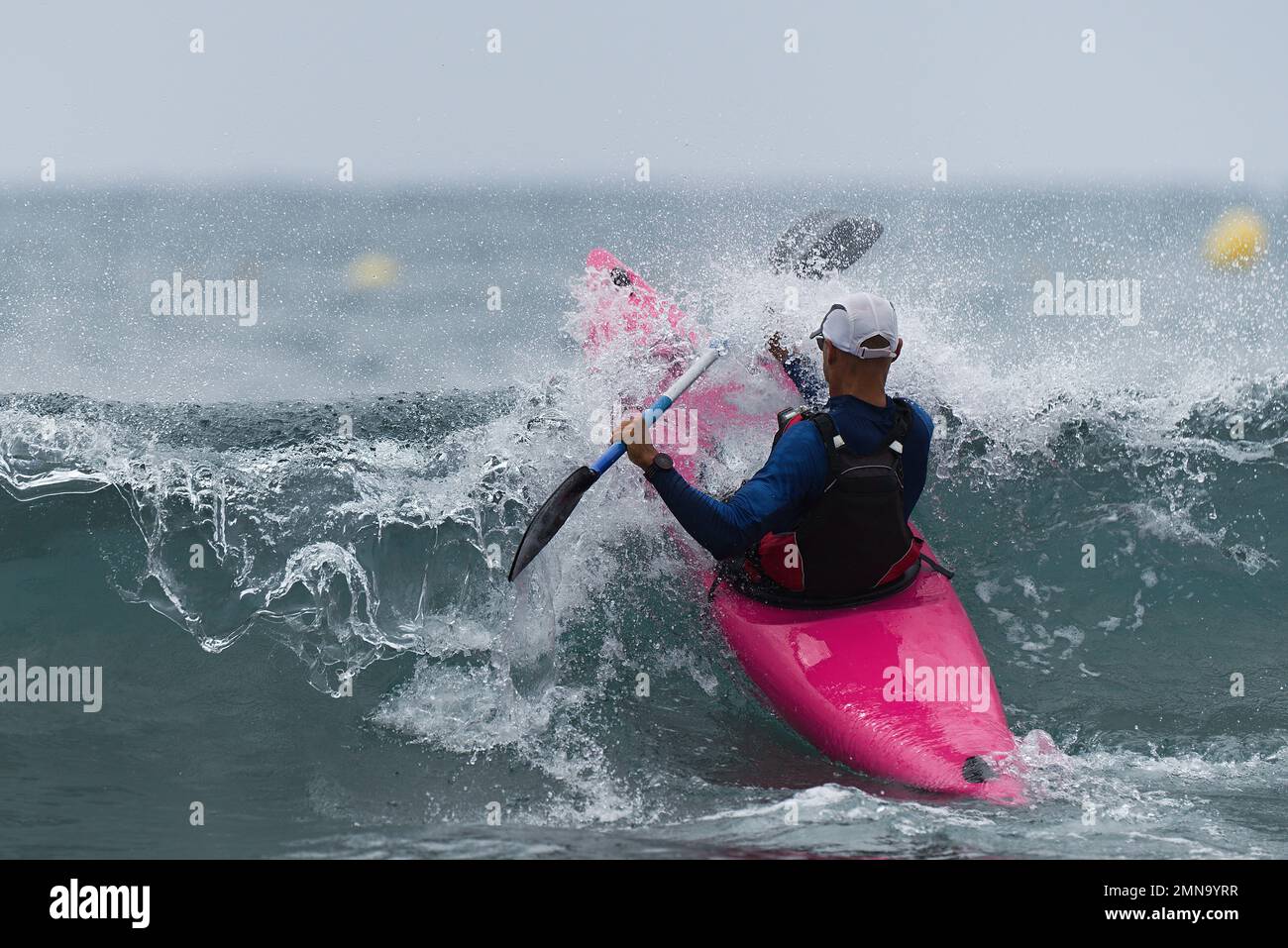 Paddlers race their ocean kayak surf skis through breaking waves Stock ...