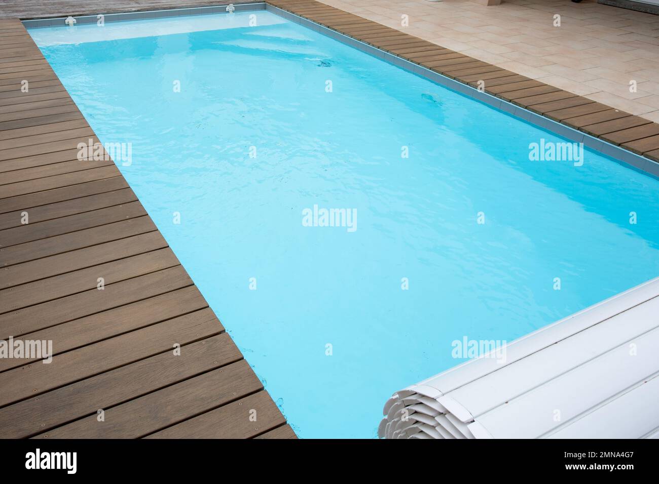 blue swimming pool with teak wood flooring in home garden summer Stock ...