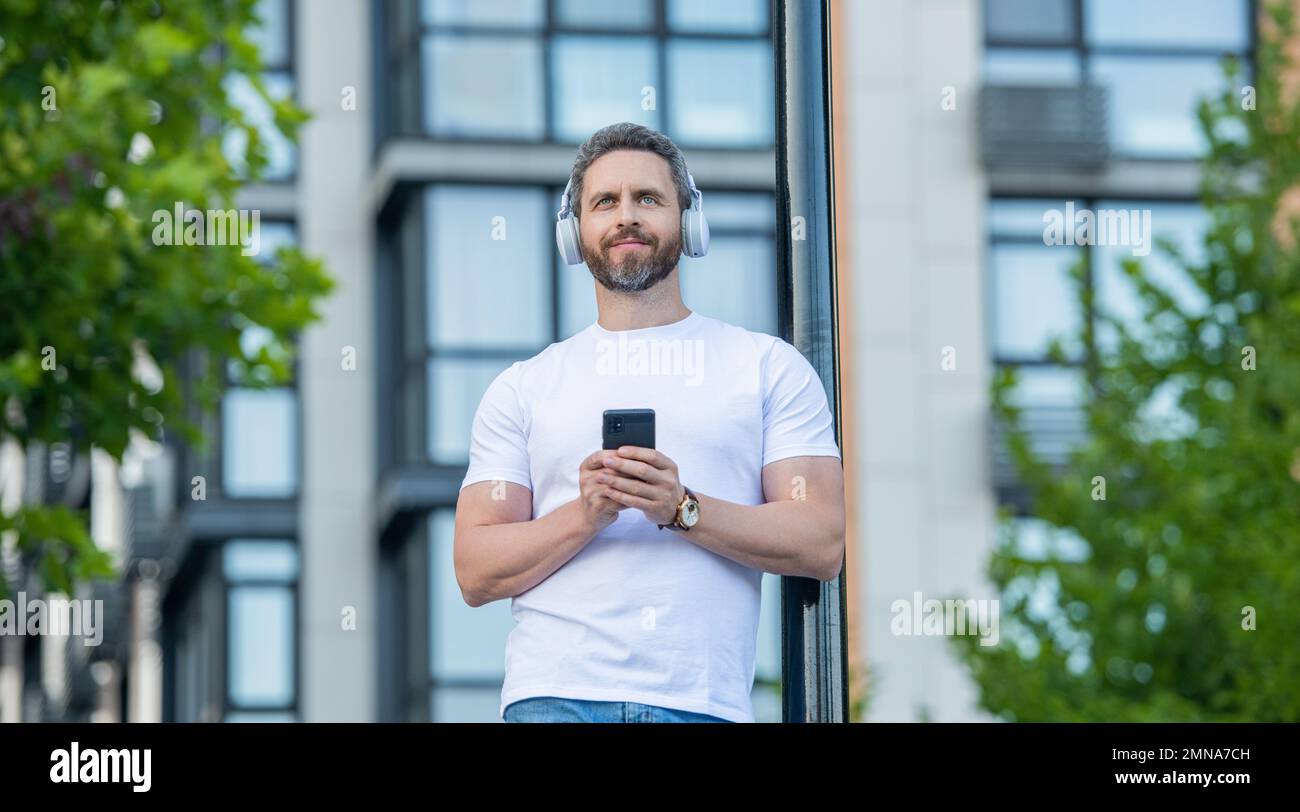 cheerful man choosing music playlist outside. photo of man choose music ...