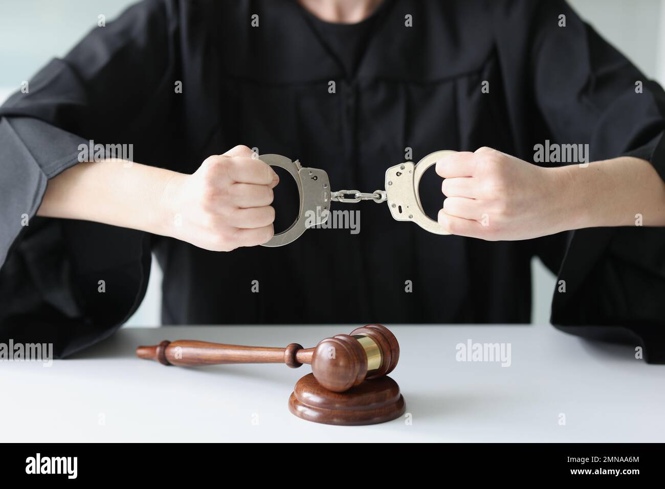 Judge sitting at table with wooden judge gavel and holding handcuffs ...