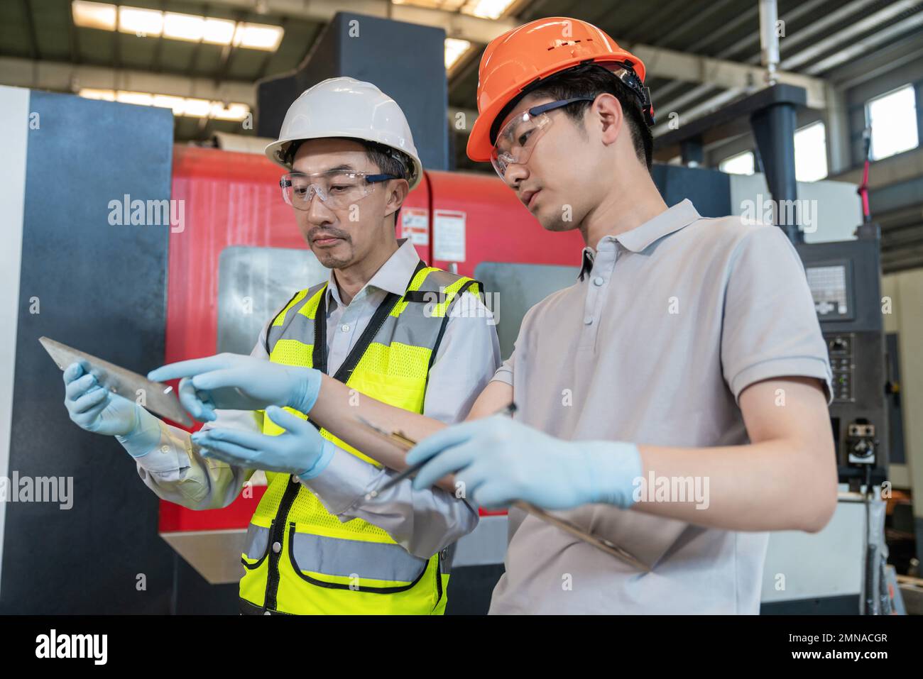 Two engineers wear protective overalls wearing helmets do measurement ...