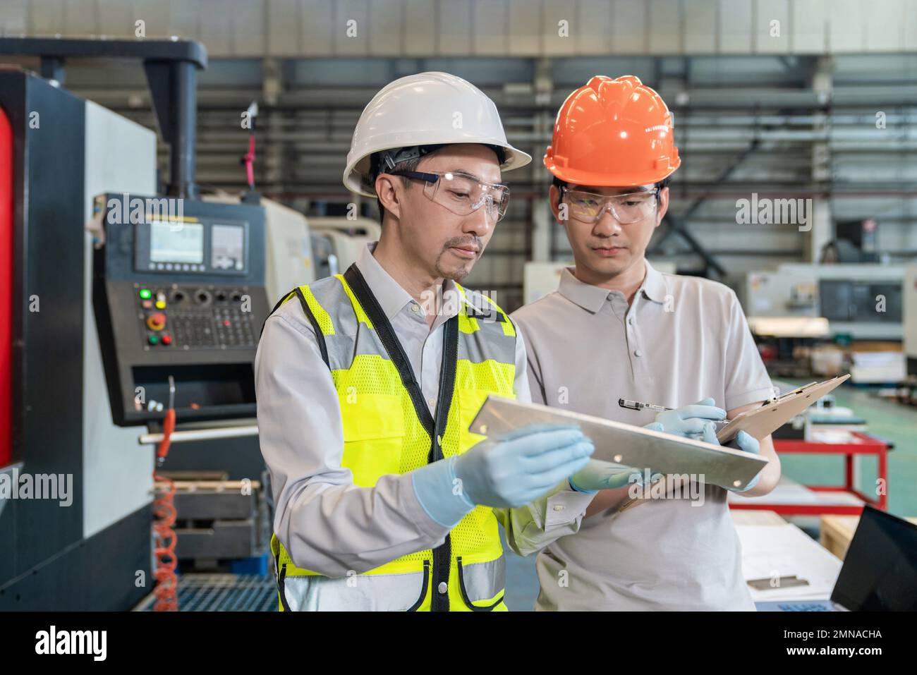 Two engineers wear protective overalls wearing helmets do measurement ...