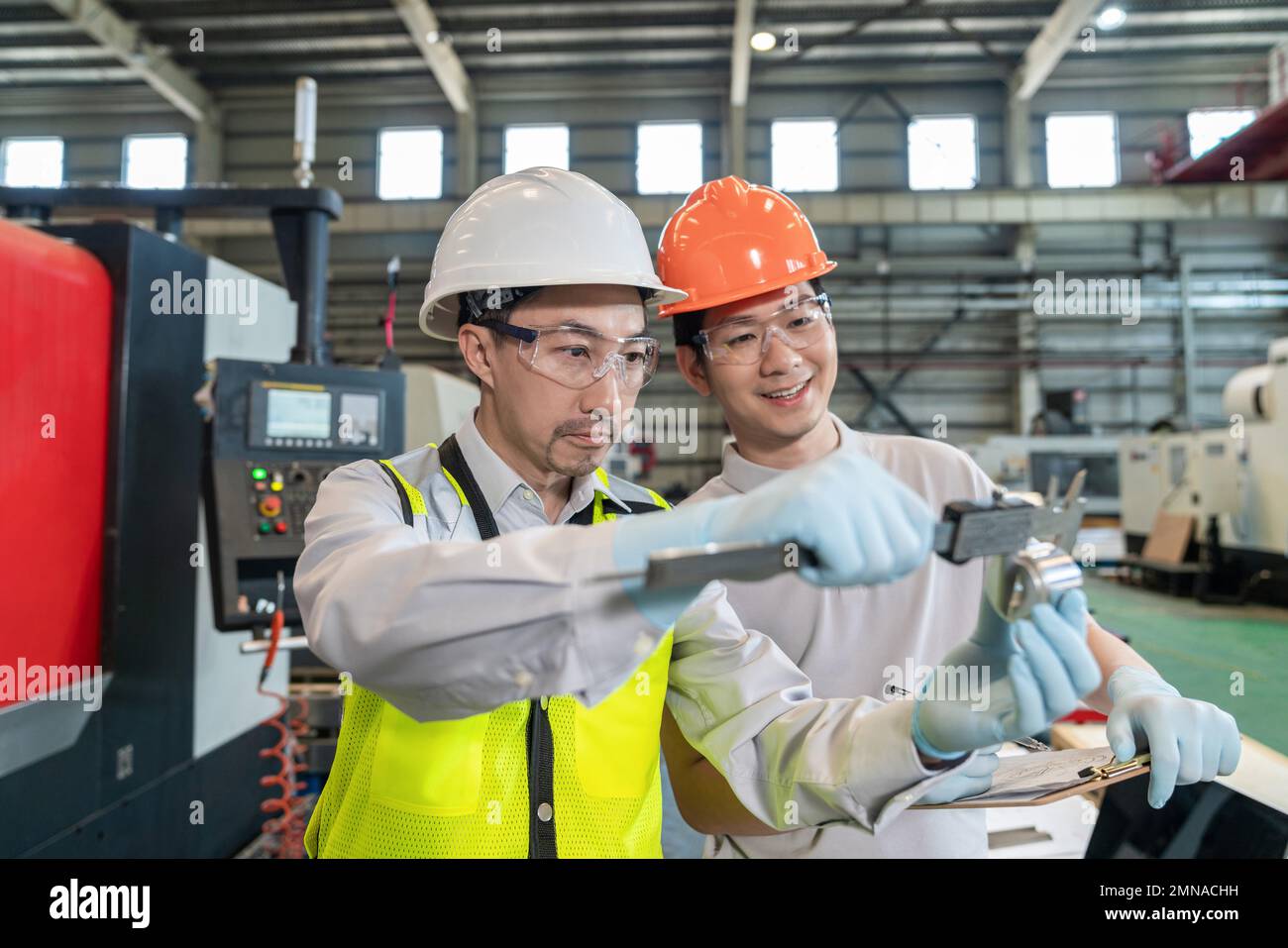 Two engineers wear protective overalls wearing helmets do measurement ...