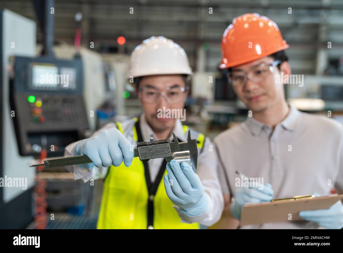 Two engineers wear protective overalls wearing helmets do measurement ...