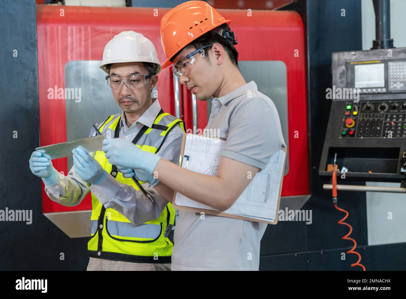 Two engineers wear protective overalls wearing helmets do measurement ...