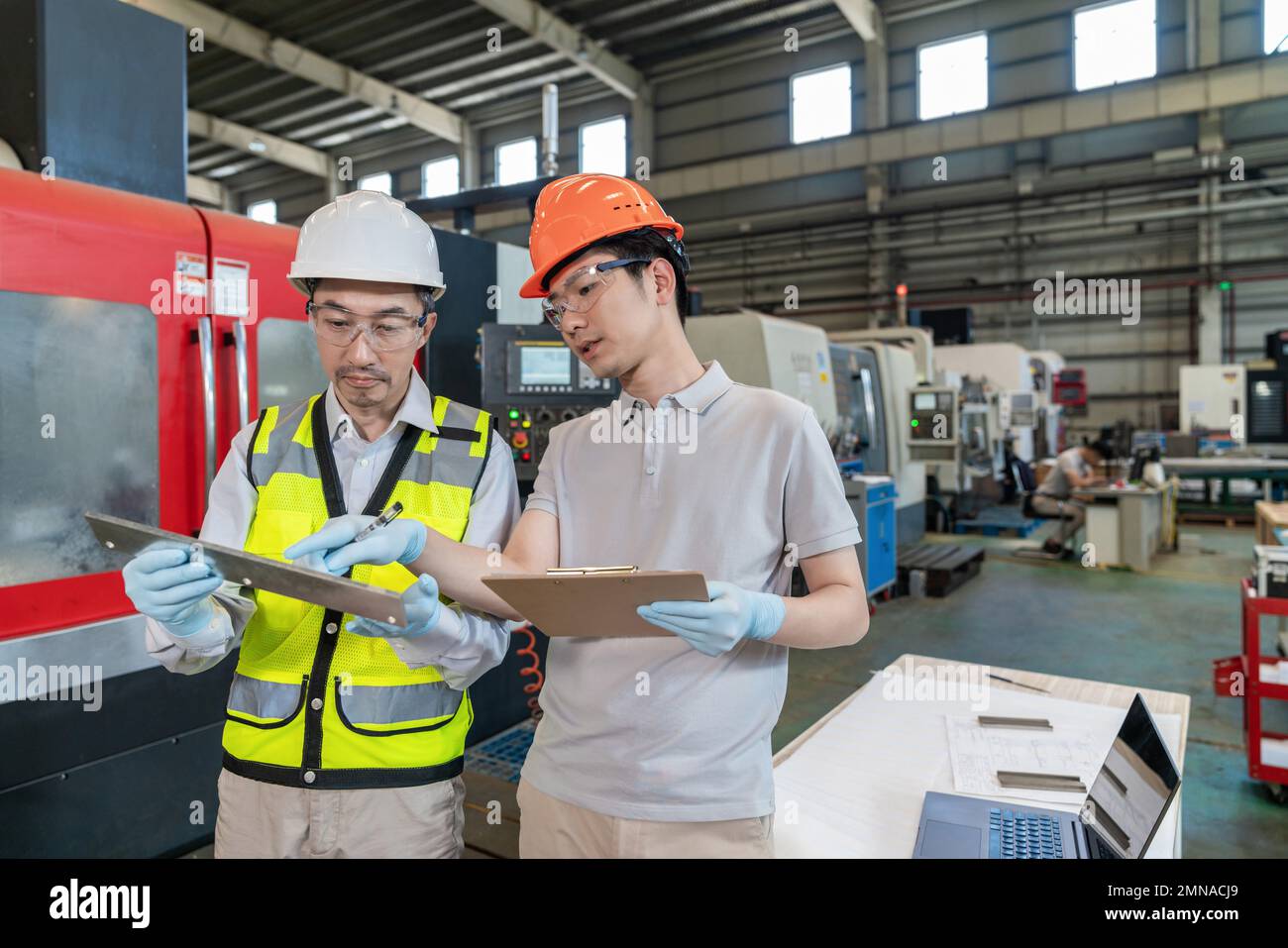Two engineers wear protective overalls wearing helmets do measurement ...