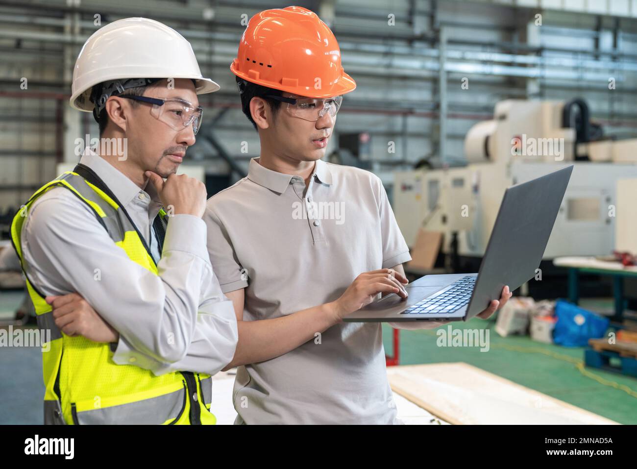 Two engineers wear protective overalls wearing helmets working in the factory Stock Photo - Alamy