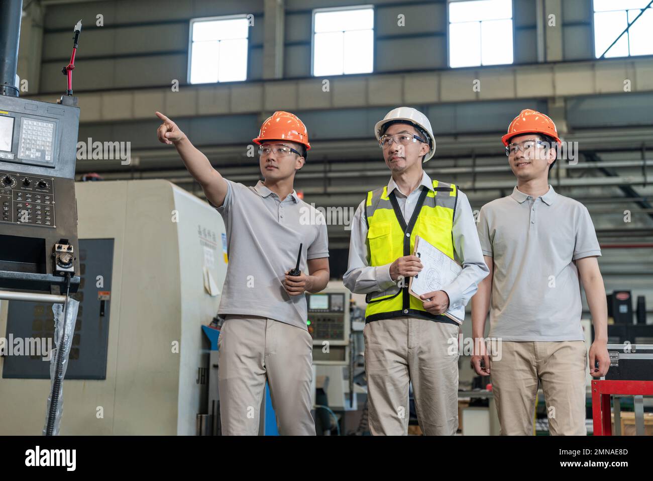 Three engineers wear protective overalls wearing helmets working in the ...