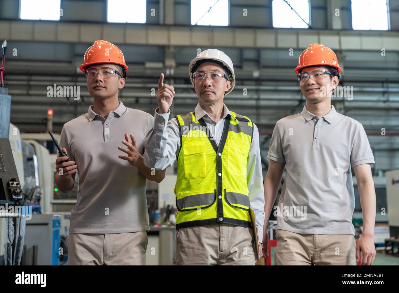 Three engineers wear protective overalls wearing helmets working in the ...