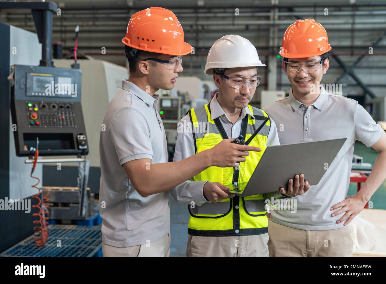 Three engineers wear protective overalls wearing helmets working in the ...