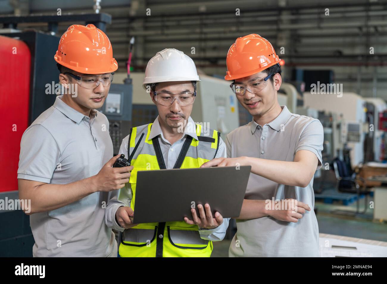 Three engineers wear protective overalls wearing helmets working in the ...