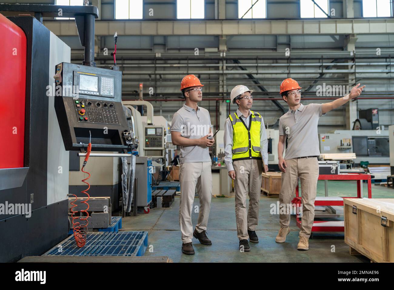 Three engineers wear protective overalls wearing helmets working in the ...