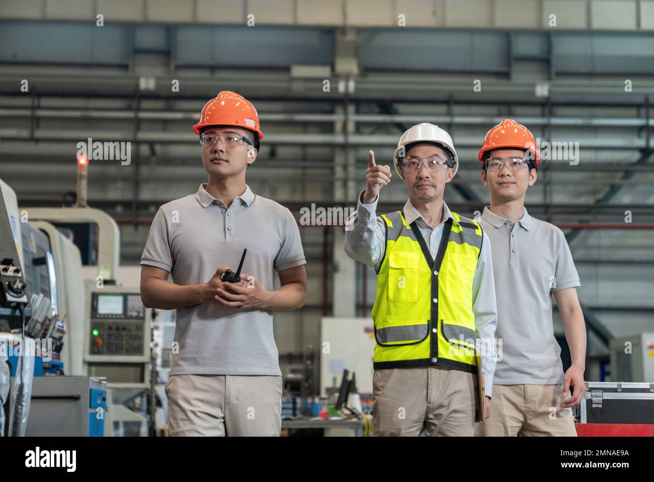 Three engineers wear protective overalls wearing helmets working in the ...