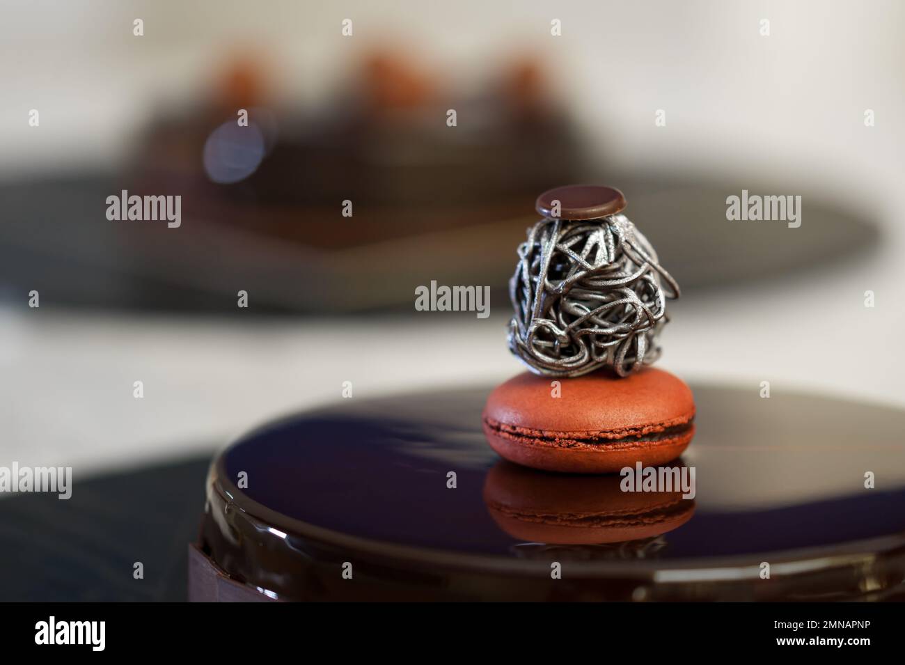 Close-up of french macaron topped with abstract silver swirls on dark ...