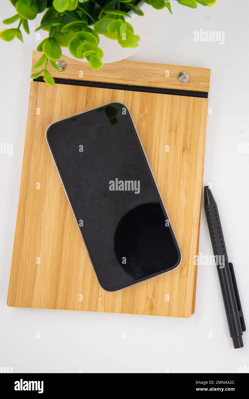 Flat lay of mobile smart phone with blank screen of gadget on notebook ...