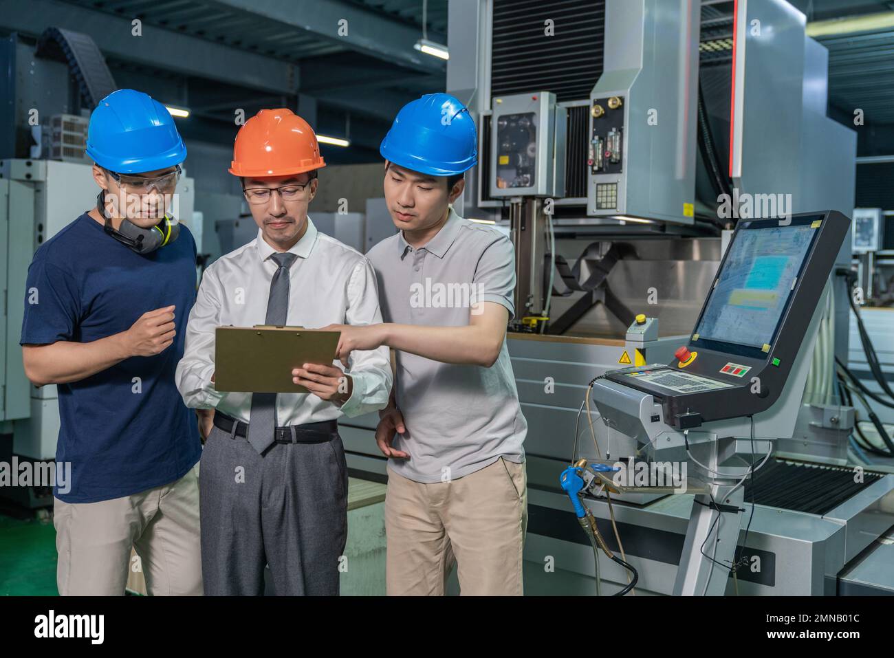 Three engineers working in the factory Stock Photo - Alamy