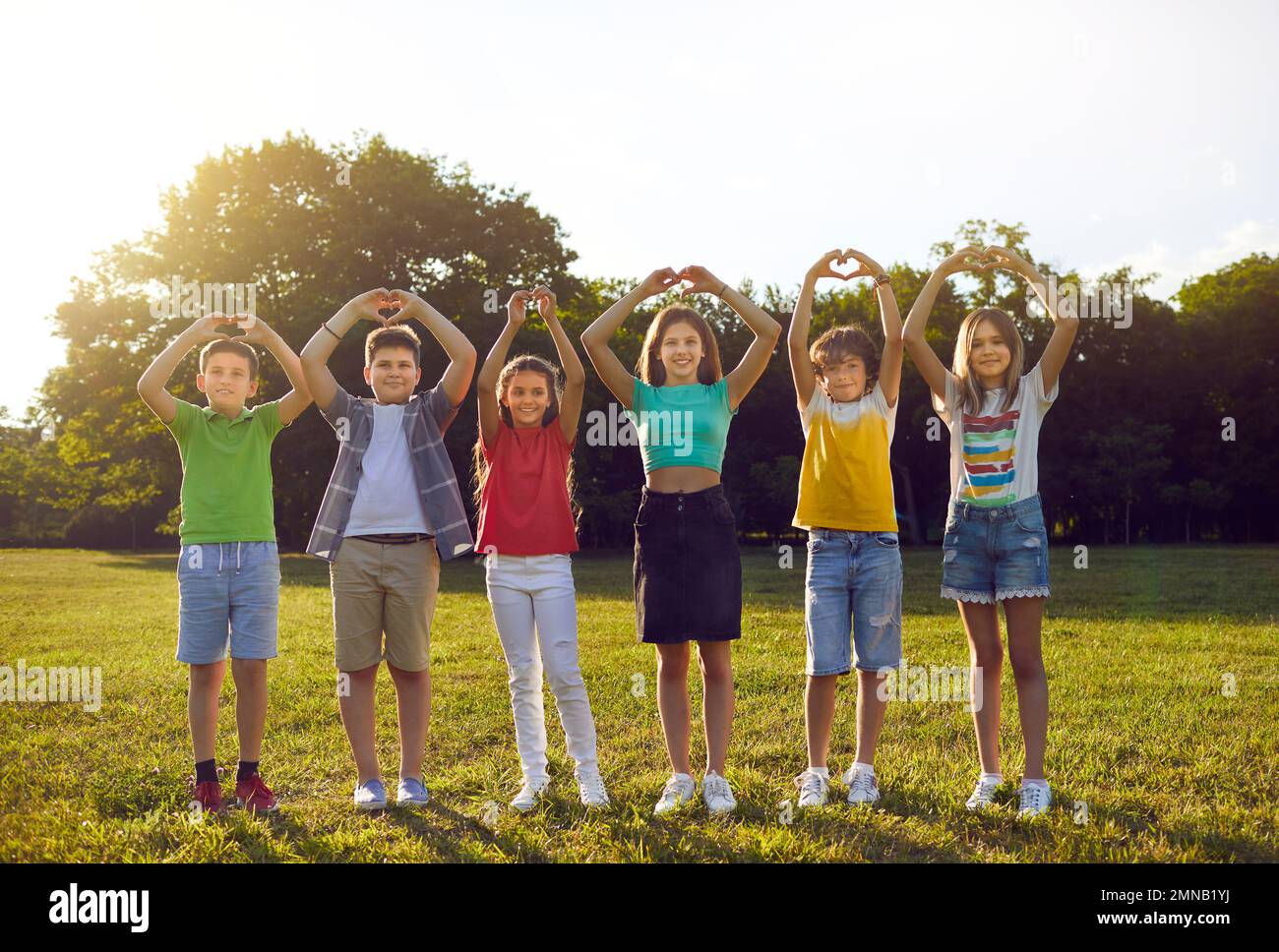 Group portrait of happy, smiling children standing in park and doing ...
