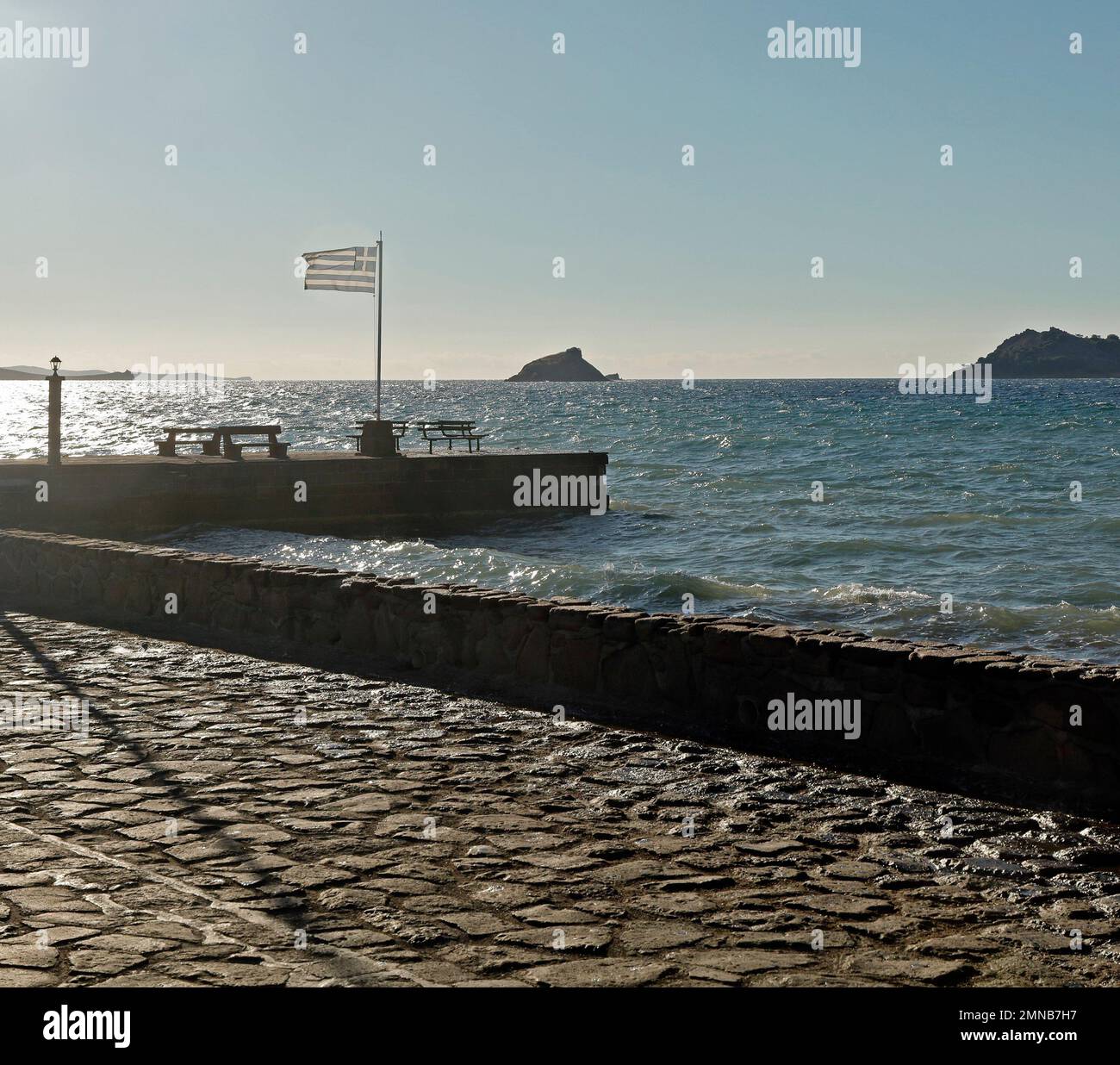 The pier at Petra village with Greek flag flying.Lesbos island ...