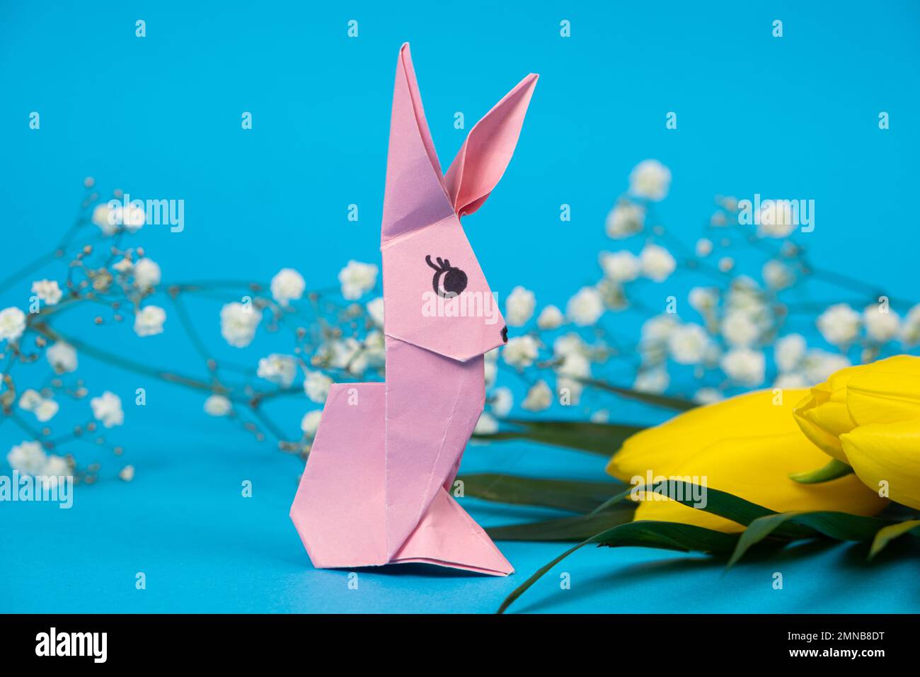 A pink origami rabbit on a blue background. Crafts for Easter, fold ...