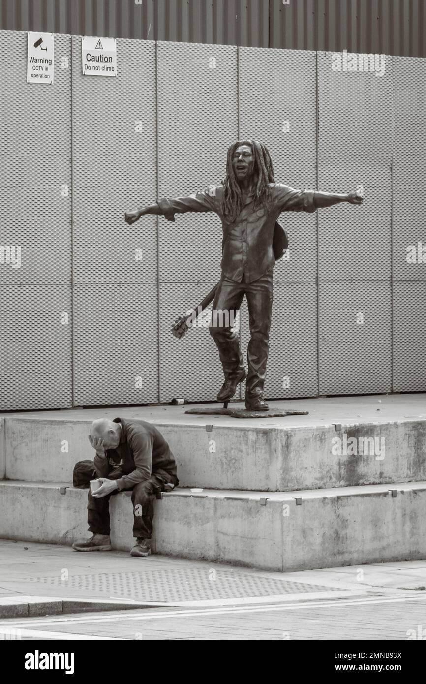Sat Man sitting in front of sculpture statue of happy Bob Marley in ...