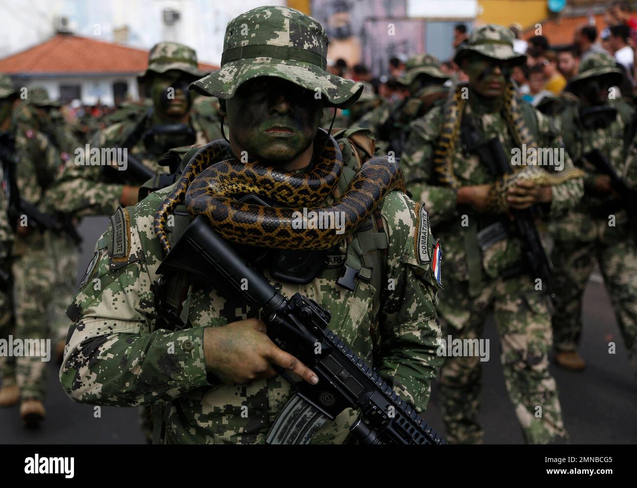 Navy officers march with snakes wrapped around their necks, in a ...