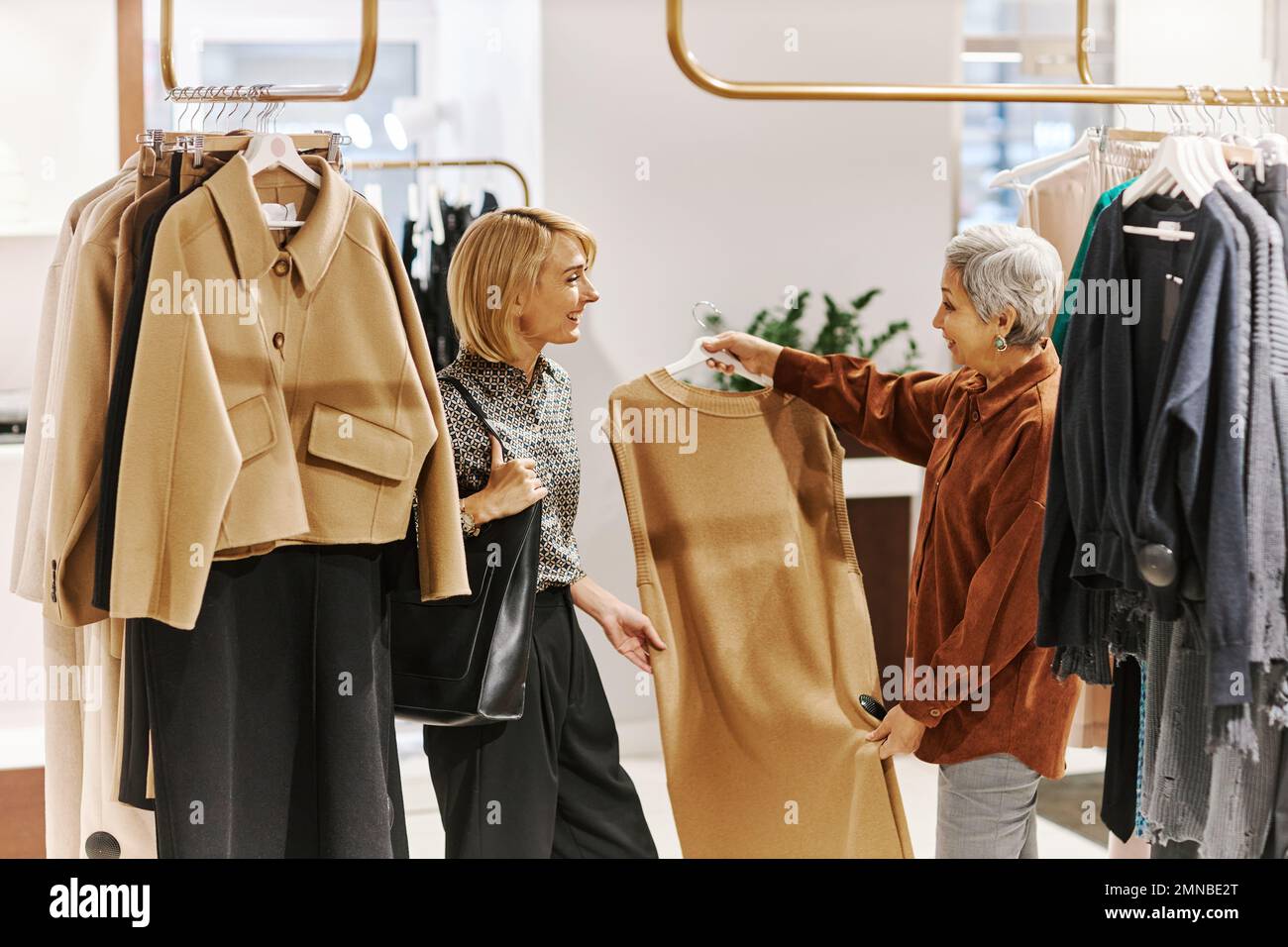 Side view portrait of sales assistant helping senior woman choosing ...