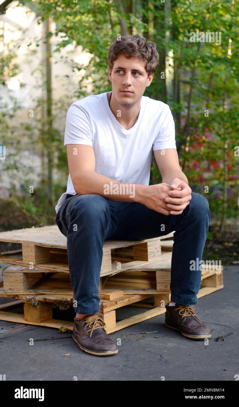 Men sitting on wooden pallets during a break Stock Photo - Alamy