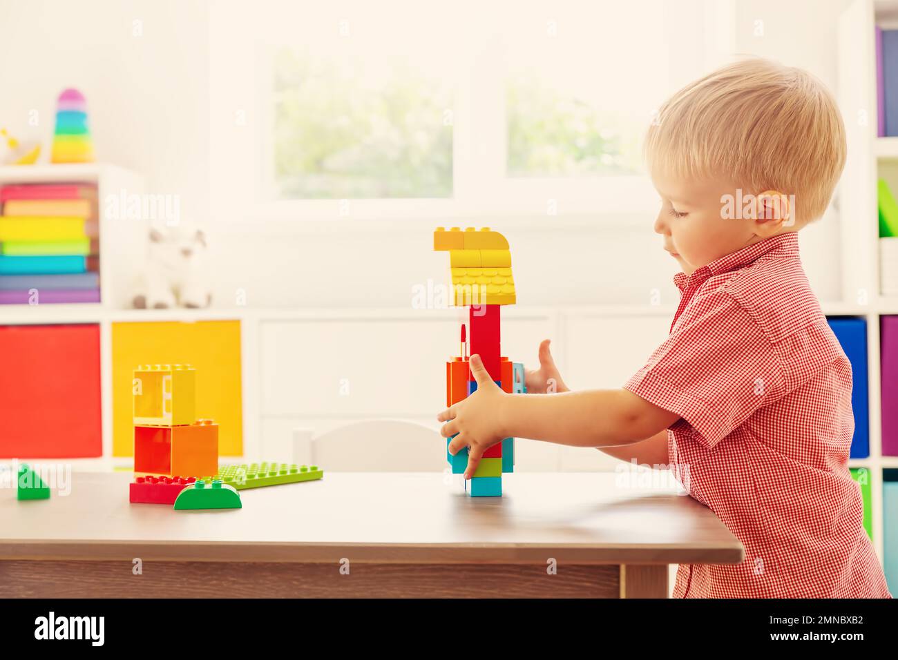 Cute child sitting at the table and playing with constructor Stock ...
