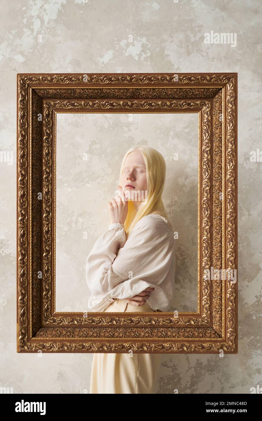 Youthful albino girl in white attire keeping eyes closed while standing ...