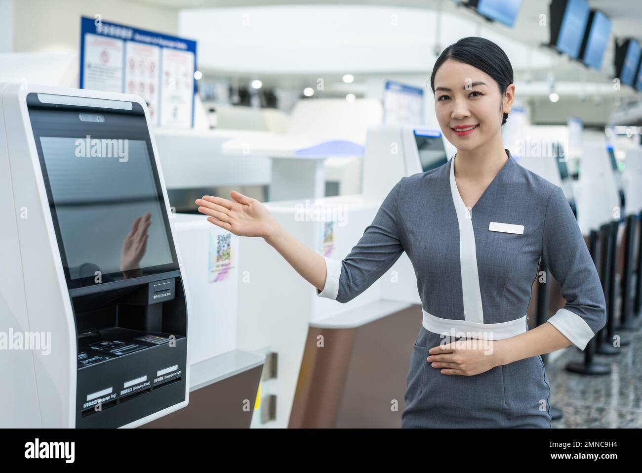 Smiling stewardess showing self-service check-in Stock Photo - Alamy