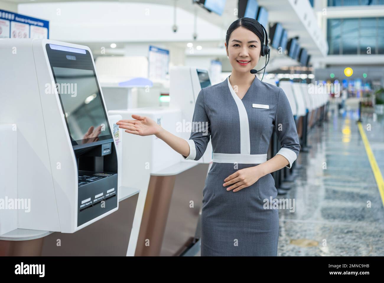 Smile of a flight attendant with headphones show self-service check-in ...