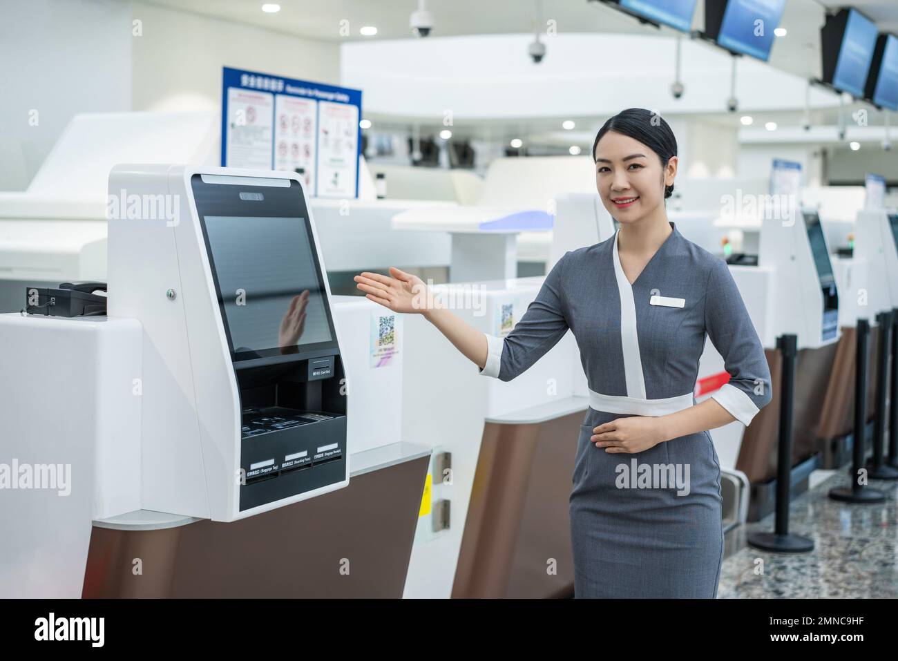 Smiling stewardess showing self-service check-in Stock Photo - Alamy