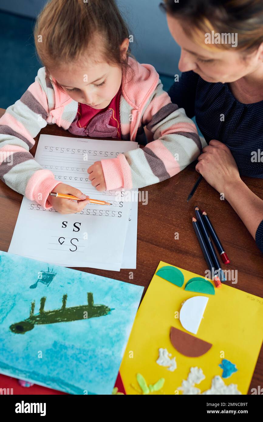 Little girl preschooler learning to write letters with help of her ...