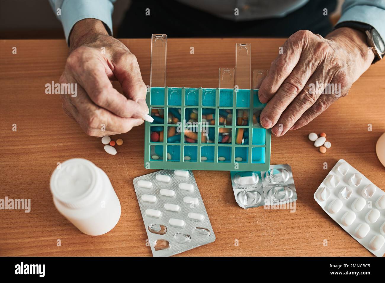 Senior man organizing his medication into pill dispenser. Senior man ...