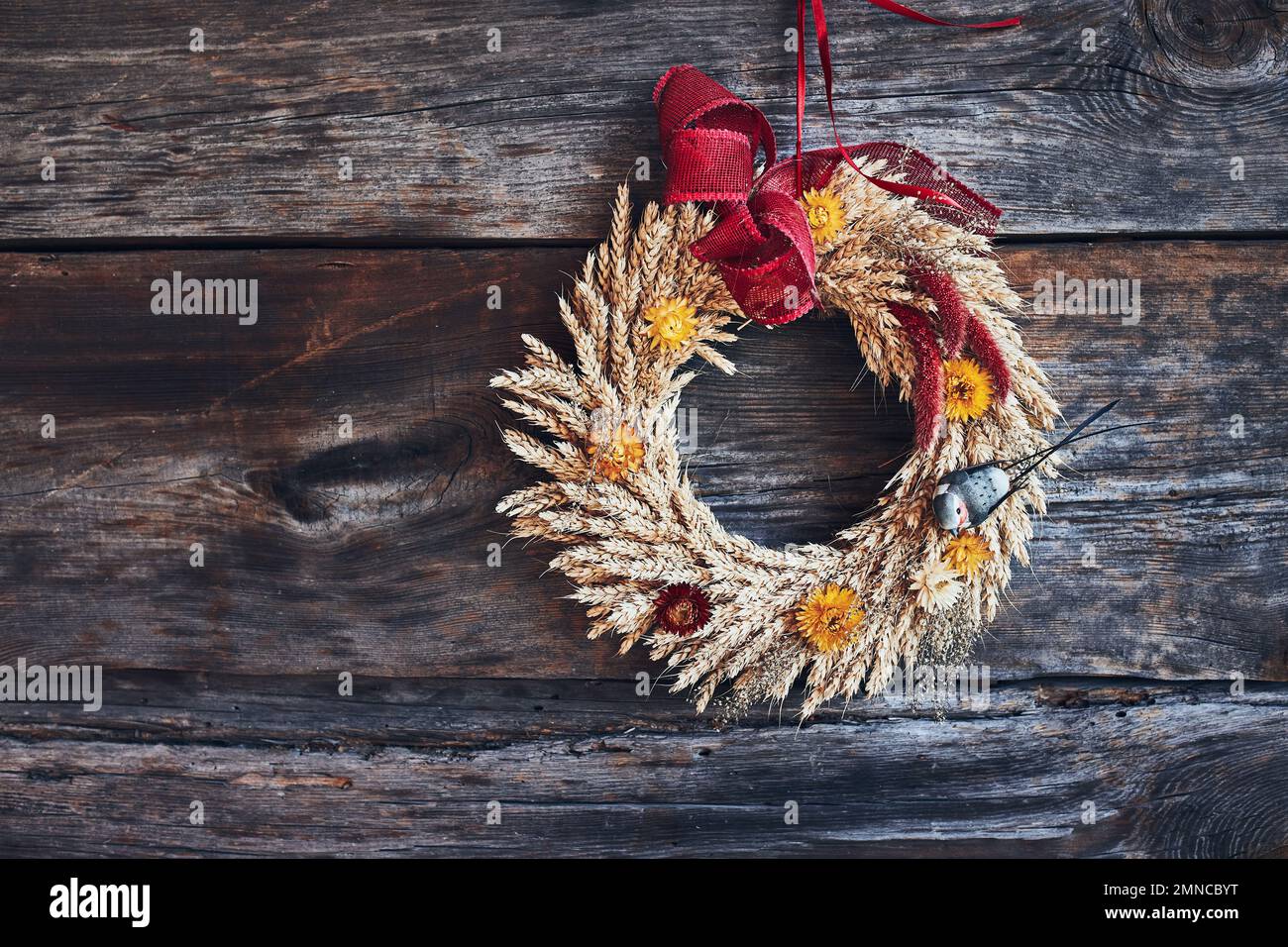 Wreath of golden ears of wheat, dried flowers and herbs tied with red ...