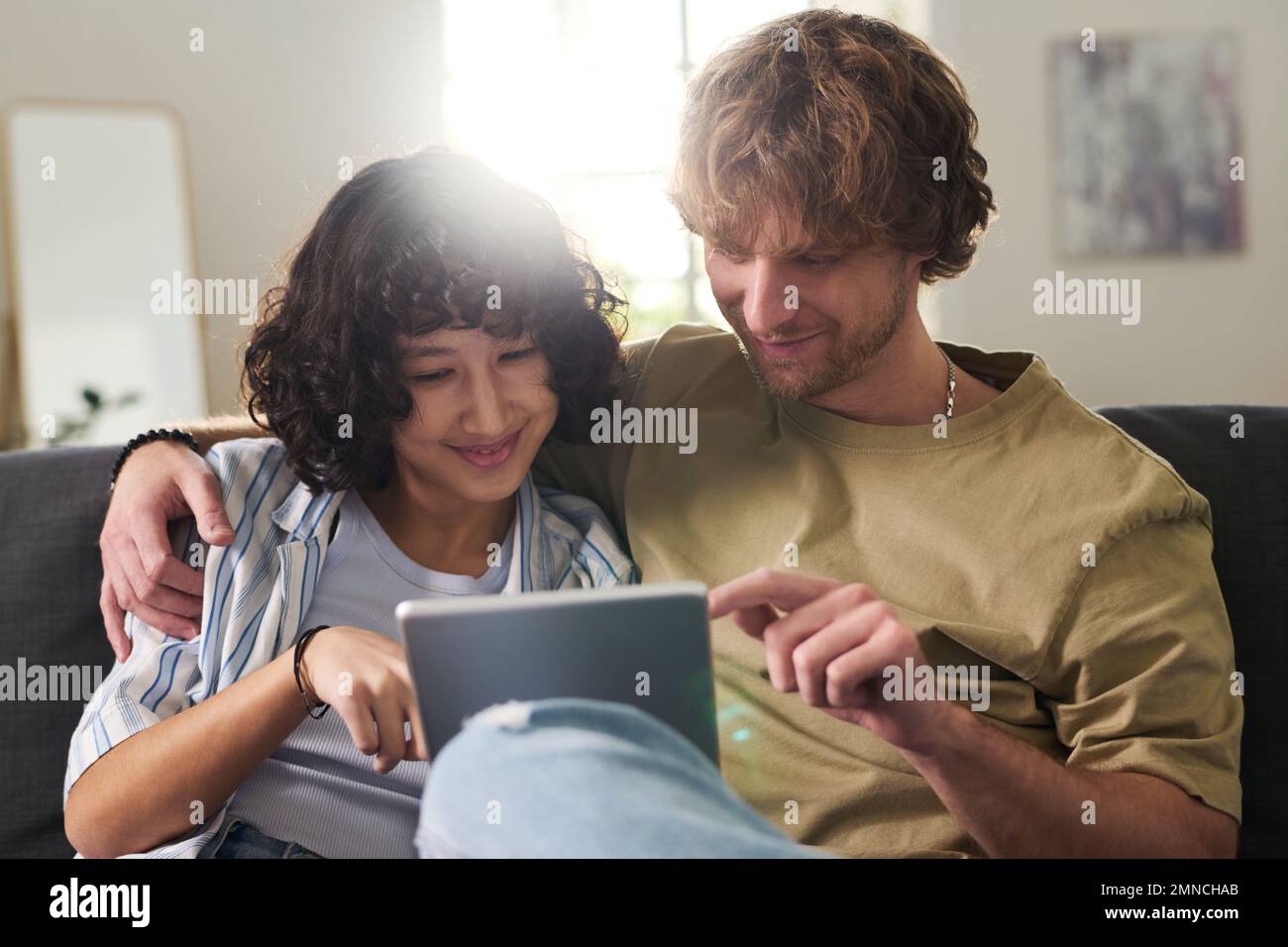 Young smiling man and woman searching for interesting online movie ...