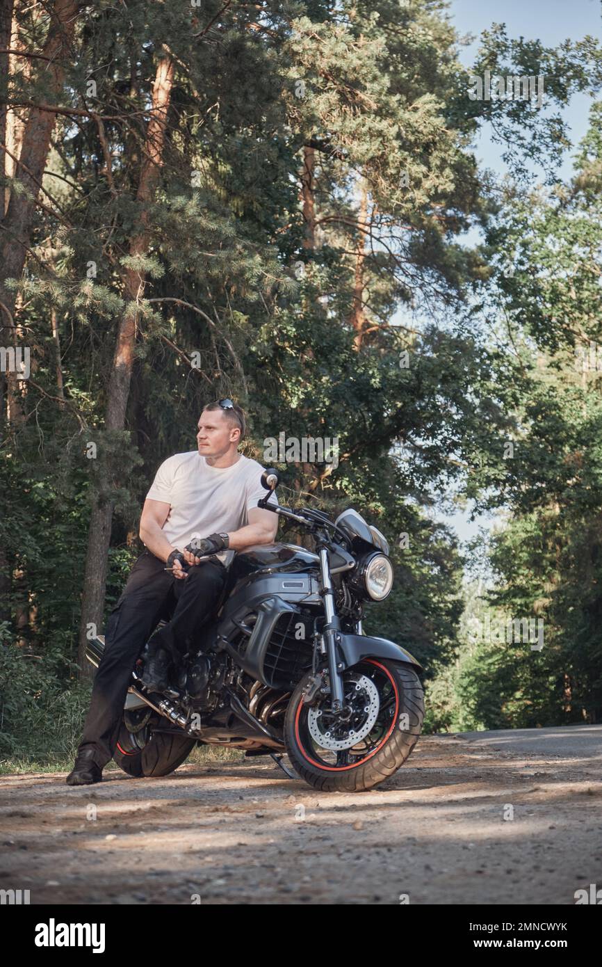 Young male biker travels on a motorcycle alone, stopped and smoking on ...