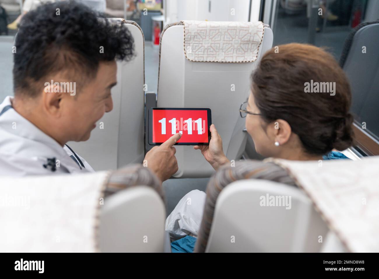 Happy elderly couple use tablet computers on the subway Stock Photo - Alamy