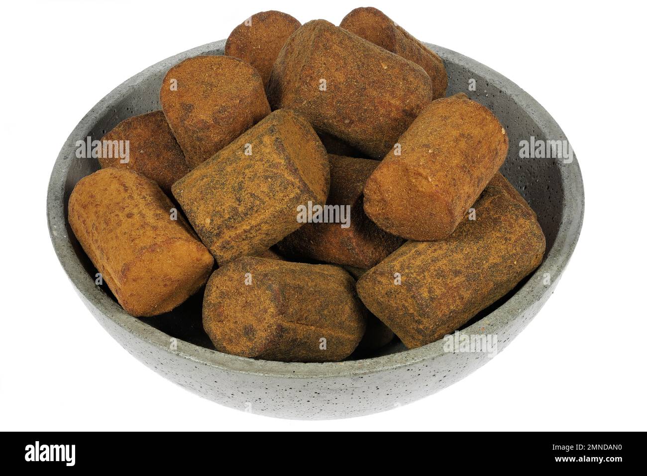 Dutch cinnamon candy sticks in a concrete bowl isolated on white ...