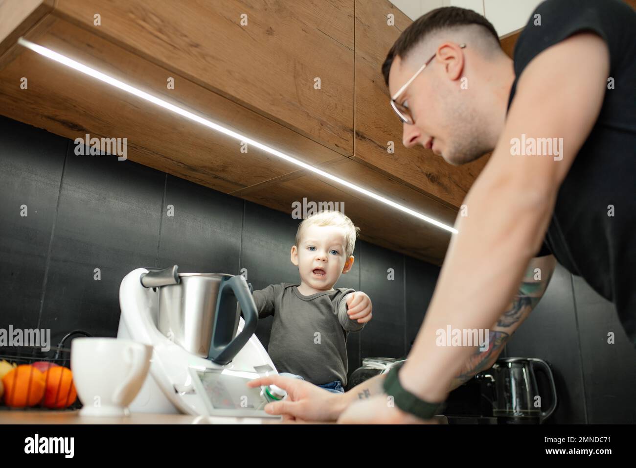 Man touch settings panel to turn on electronic blender. Little child ...