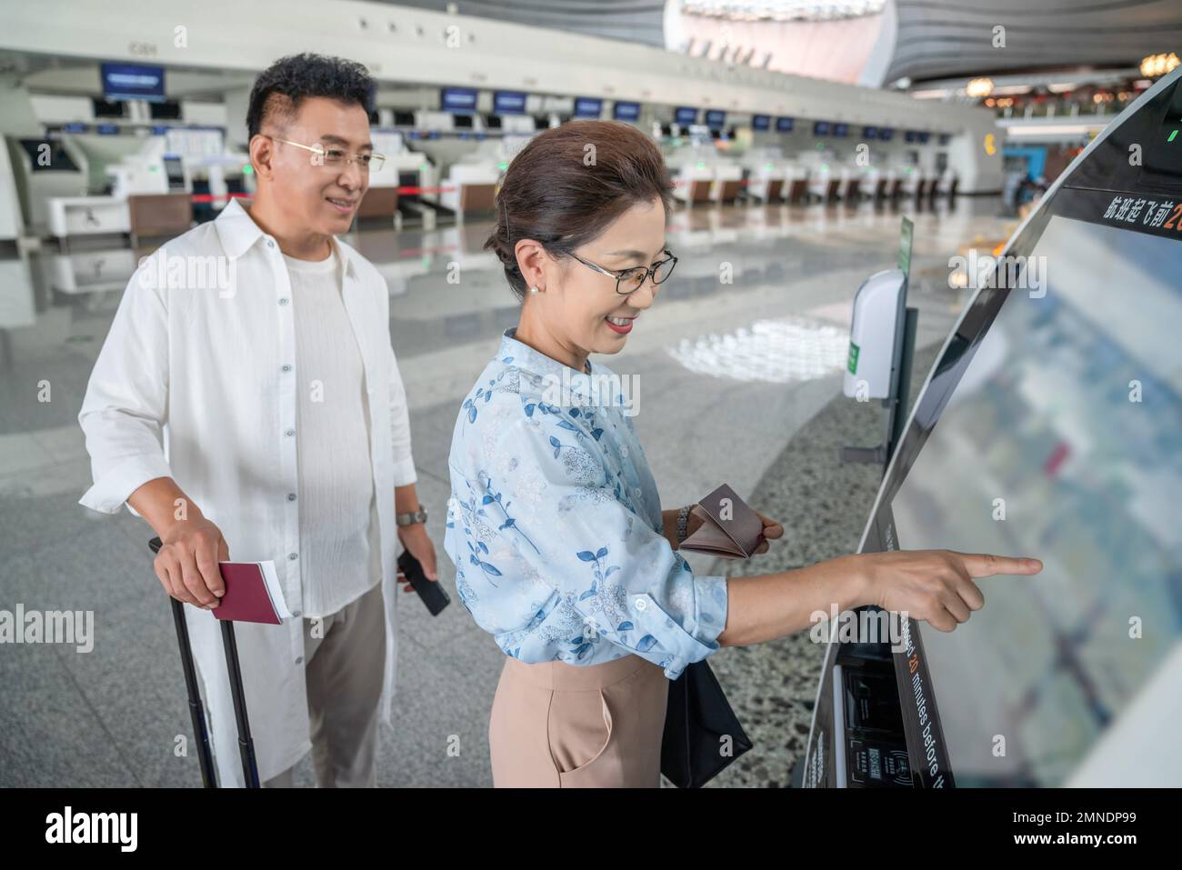 Happy elderly couple self-service ticket at the airport Stock Photo - Alamy