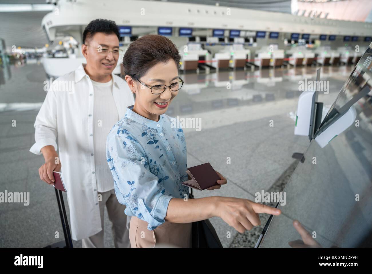 Happy elderly couple self-service ticket at the airport Stock Photo - Alamy